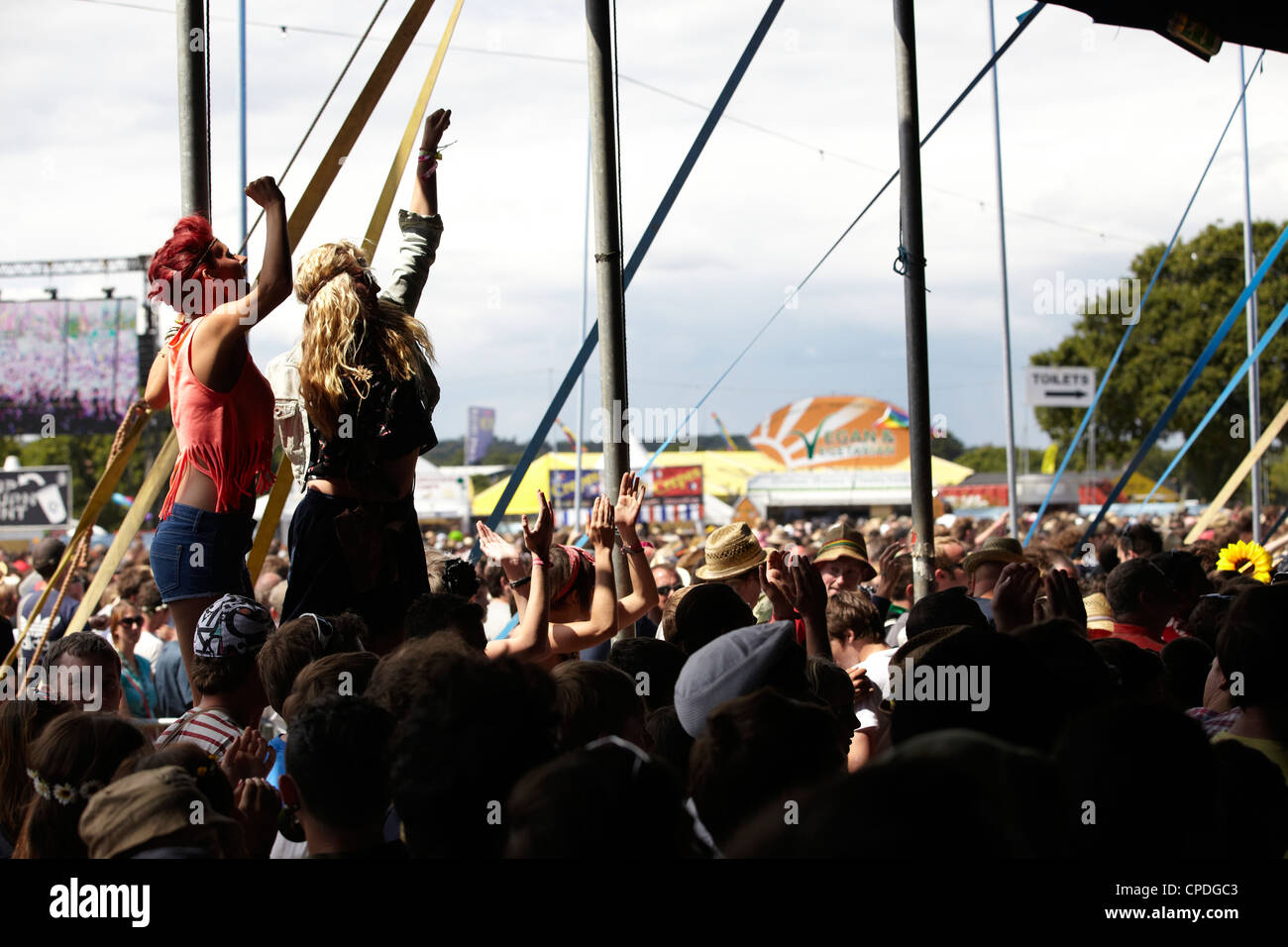 Girl on shoulders cheering in the crowd at gig at a music festival ...