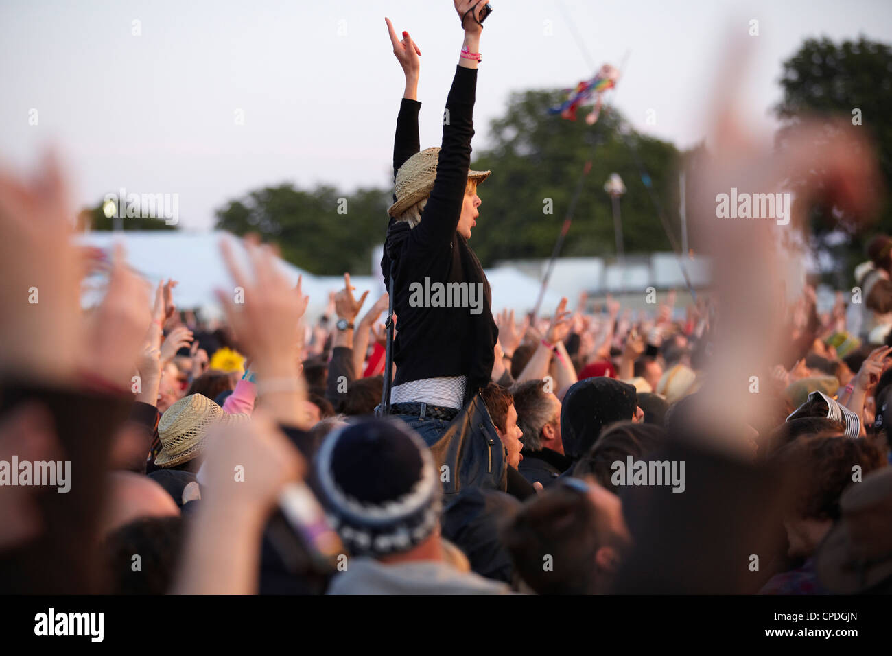 Girl on shoulders cheering while watching a gig at a music festival ...