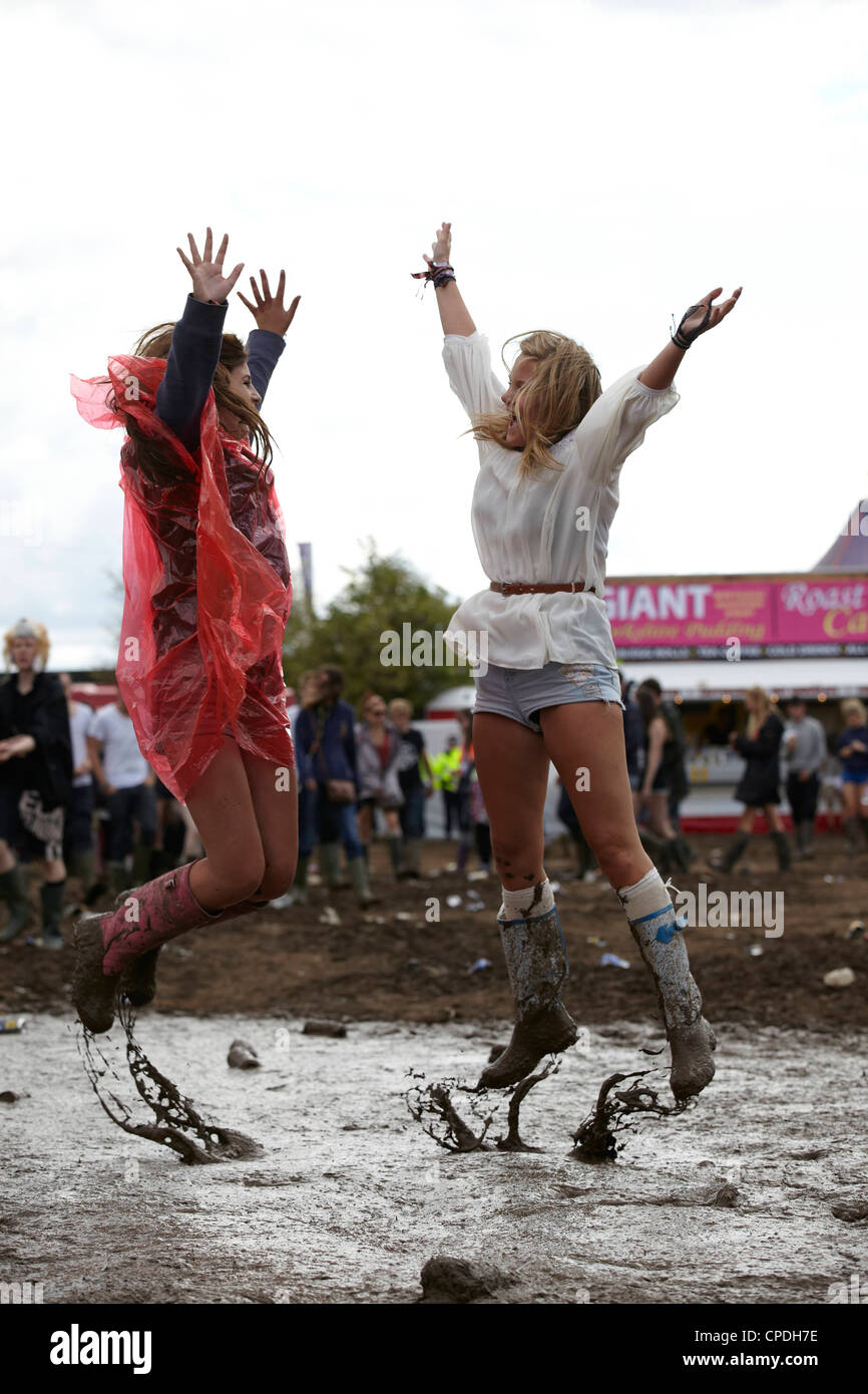 Two girls jumping and playing in the mud at a music festival Stock ...