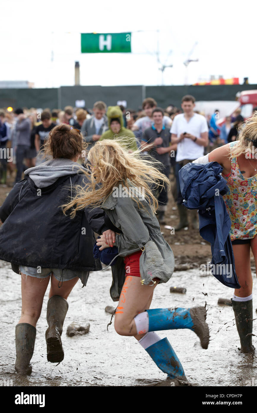 Group of girls running around in the mud at a music festival in the UK ...
