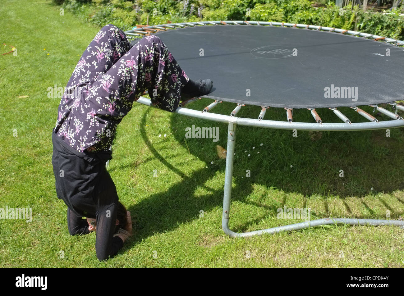 A woman practices yoga using a trampoline Stock Photo - Alamy