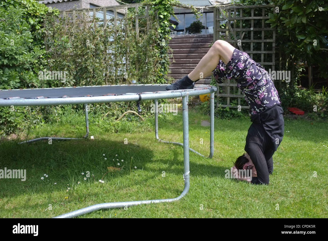 A woman practices yoga using a trampoline Stock Photo - Alamy