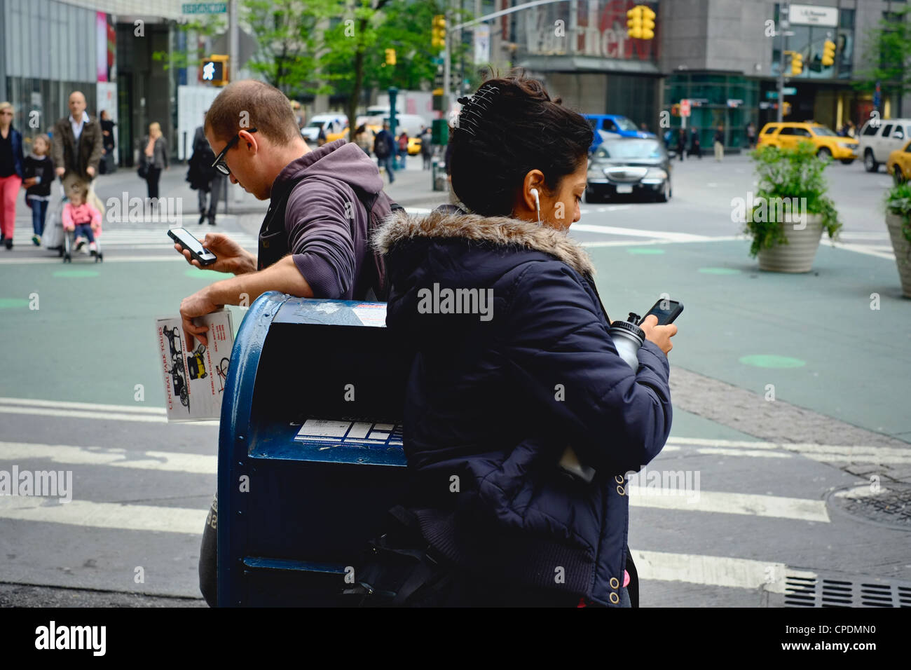Two people leaning on mail box while using iPhones near Columbus Circle ...