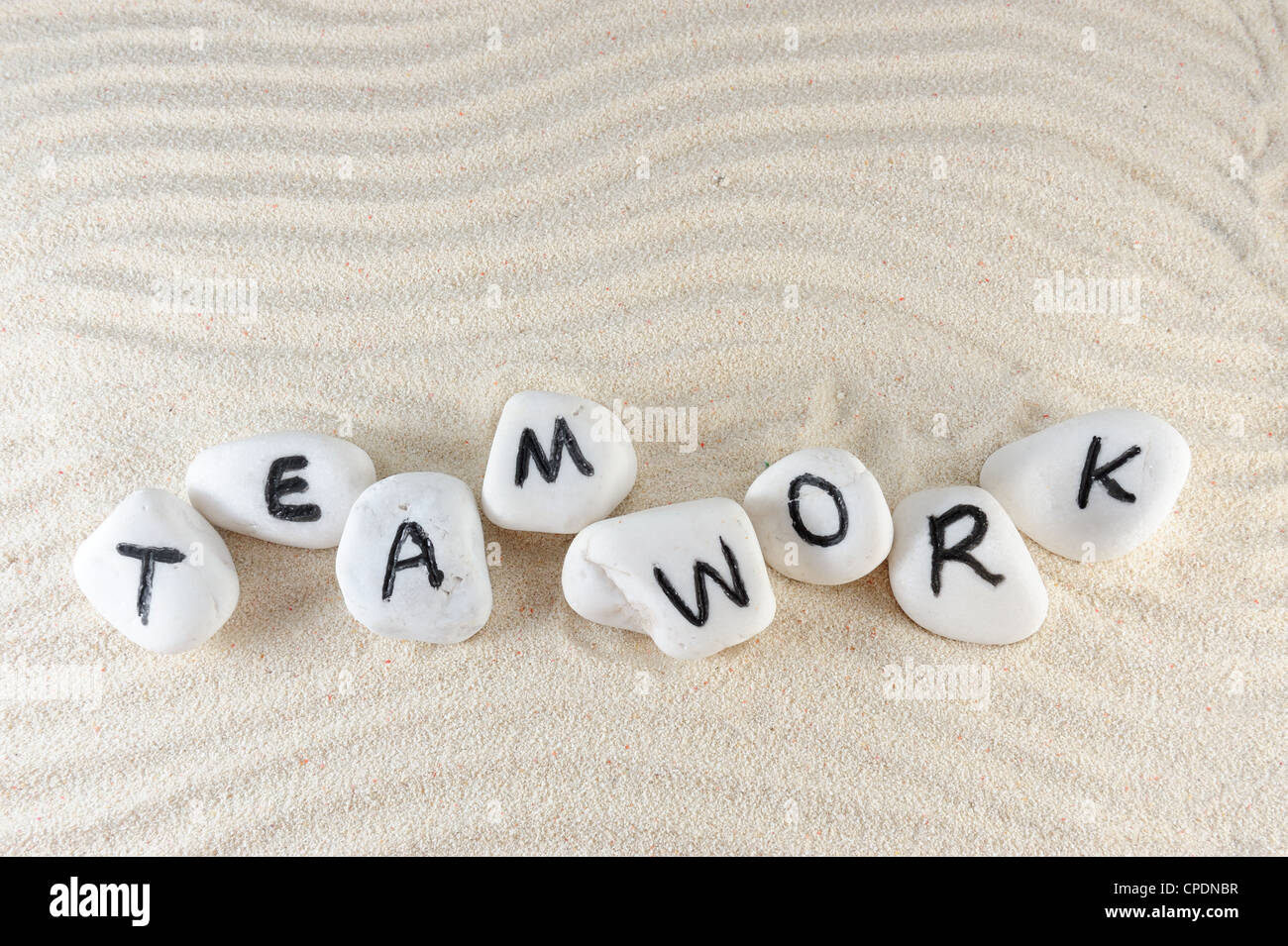 Teamwork word on group of stones with sand background Stock Photo - Alamy