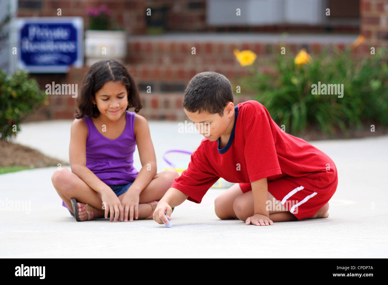 Girl and boy in their driveway playing with chalk Stock Photo - Alamy