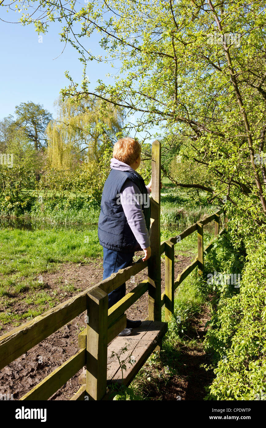 A rambler negotiates a footpath stile on her walk along the "River Bure ...