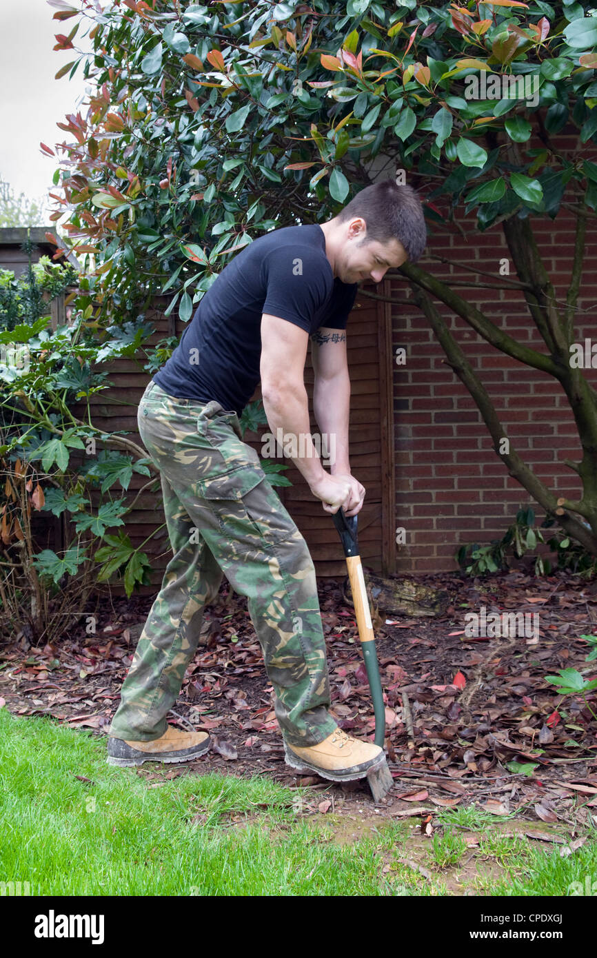 Caucasian man digging out border with garden spade in garden in Bristol ...