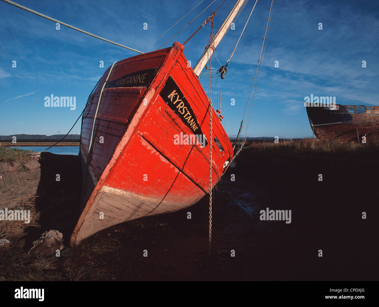 A bright red boat hauled up on the south bank of the River Tay under a ...