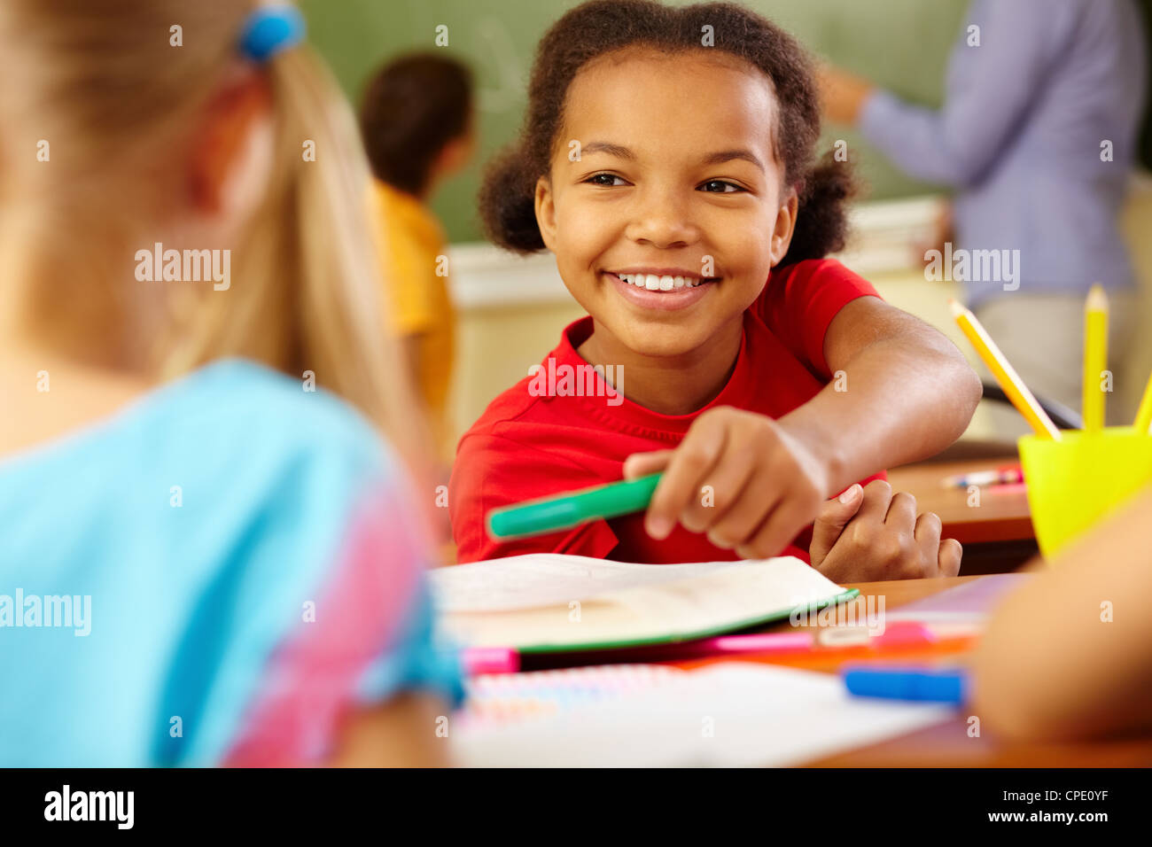 Portrait of cute girl giving crayon to classmate at lesson Stock Photo ...