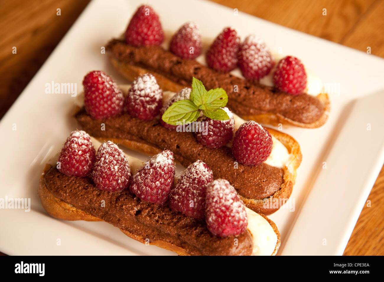 Chocolate eclairs topped with raspberries, French cafe, France, Europe ...