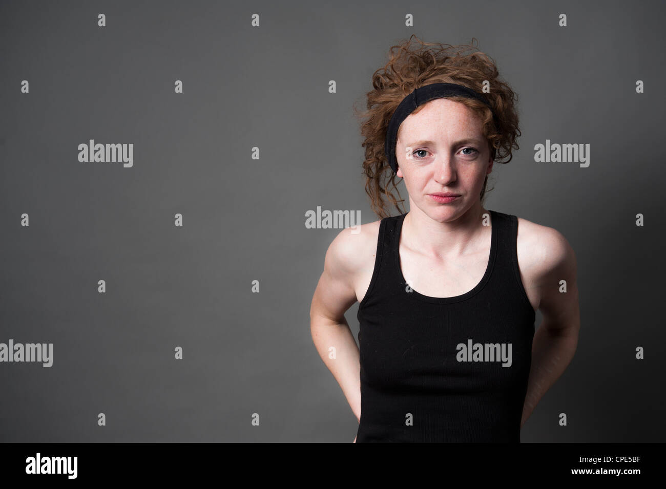 A slim dishevelled 'alternative' woman, standing in front of grey gray ...