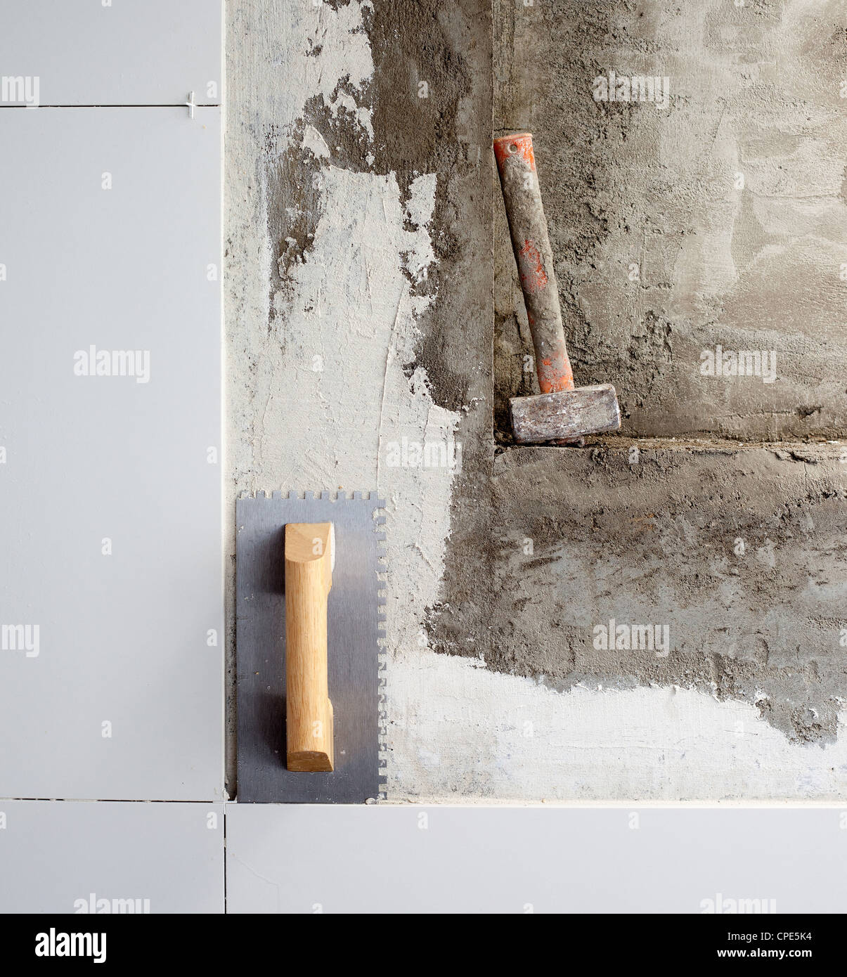 construction tools notched trowel and hammer on tiles mortar wall Stock ...