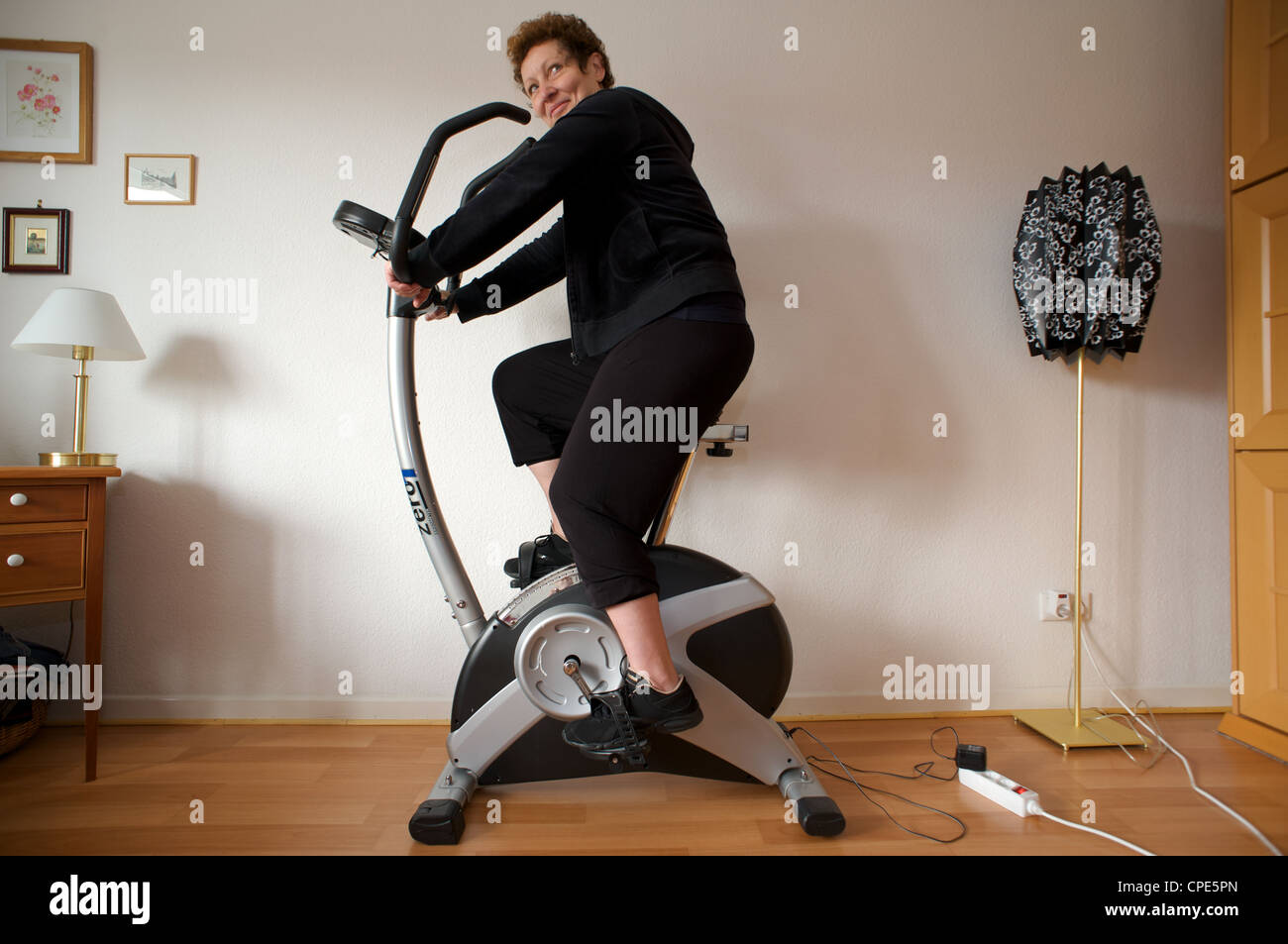 Woman at home using an exercise bike Stock Photo - Alamy
