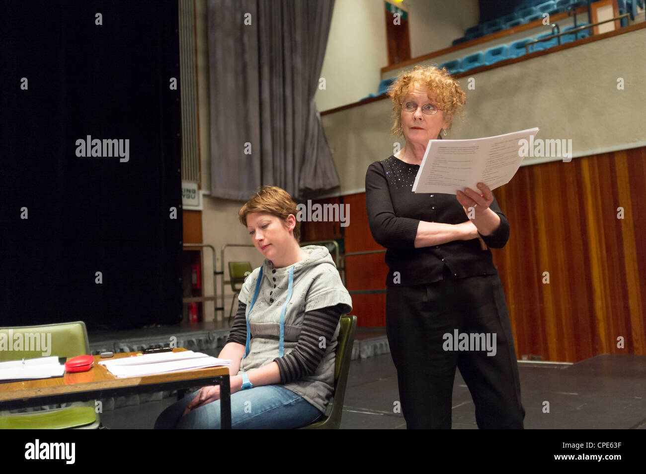 A group of amateur actors on stage holding their scripts rehearsing a ...