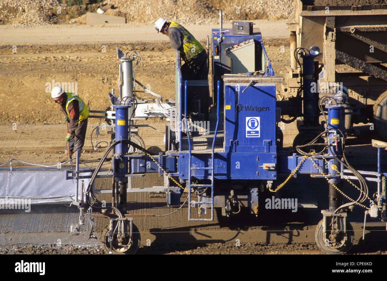 construction workers and surfacing machine laying road surface for the ...