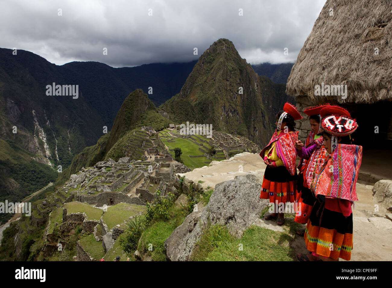 Traditionally dressed children looking over the ruins of the Inca city ...