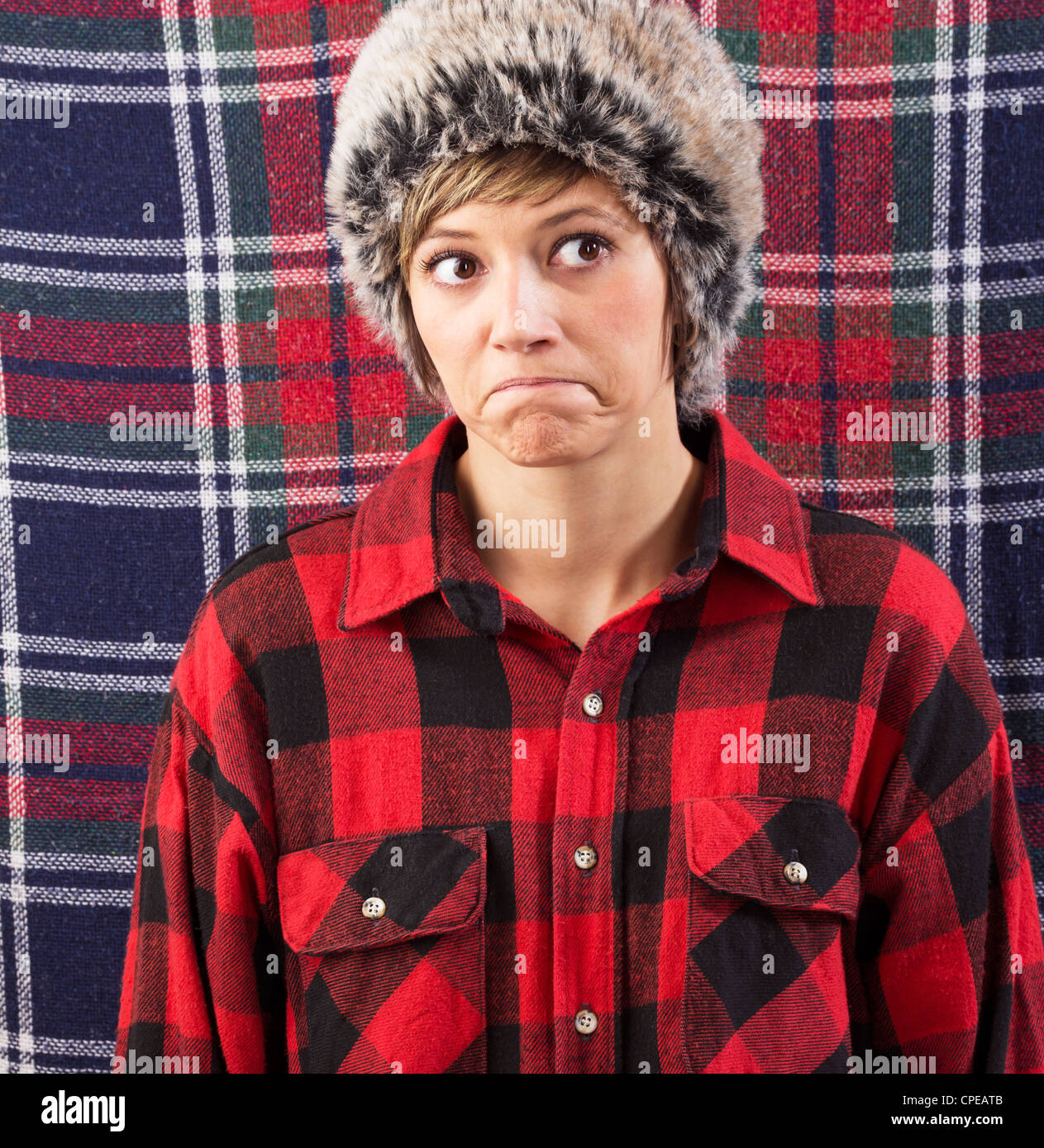 Skeptical pouting young woman wearing a checkered lumberjack shirt and ...