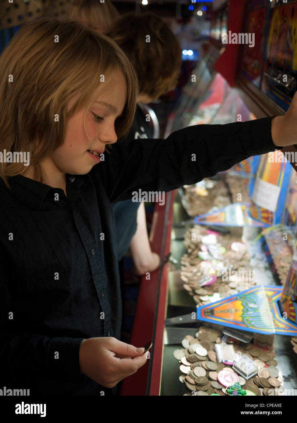 A pre-teen boy playing a Penny Waterfall machine in an amusement arcade ...