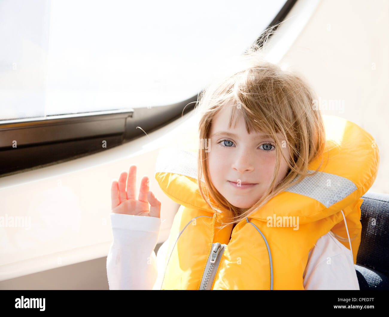 blond kid girl with marine yellow lifesaver jacket in a boat interior ...