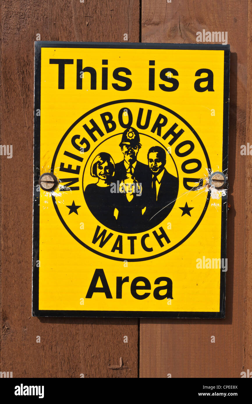 A yellow Neighbourhood Watch street sign on a brown fence Stock Photo ...