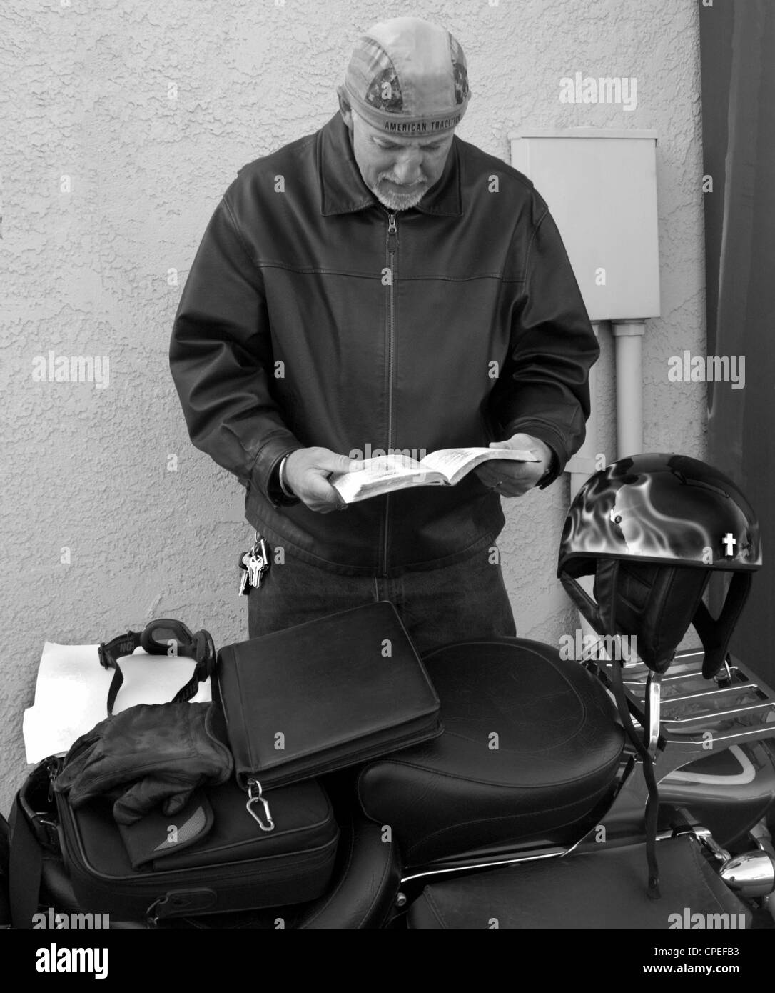 A Pastor reads his Bible over his Harley-Davidson motorcycle, next to ...