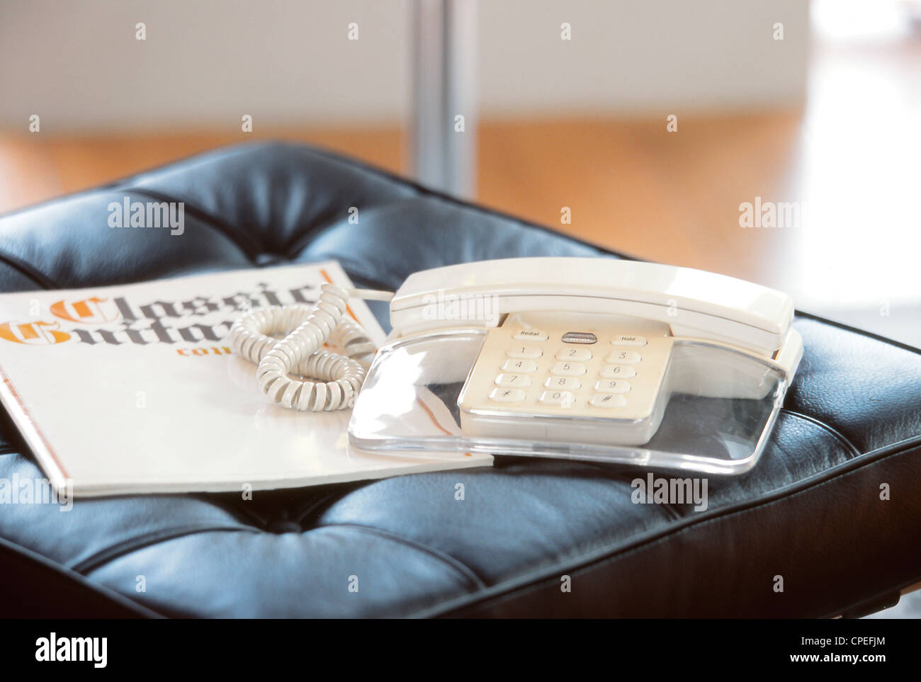 Telephone And Book On Leather Chair Stock Photo - Alamy