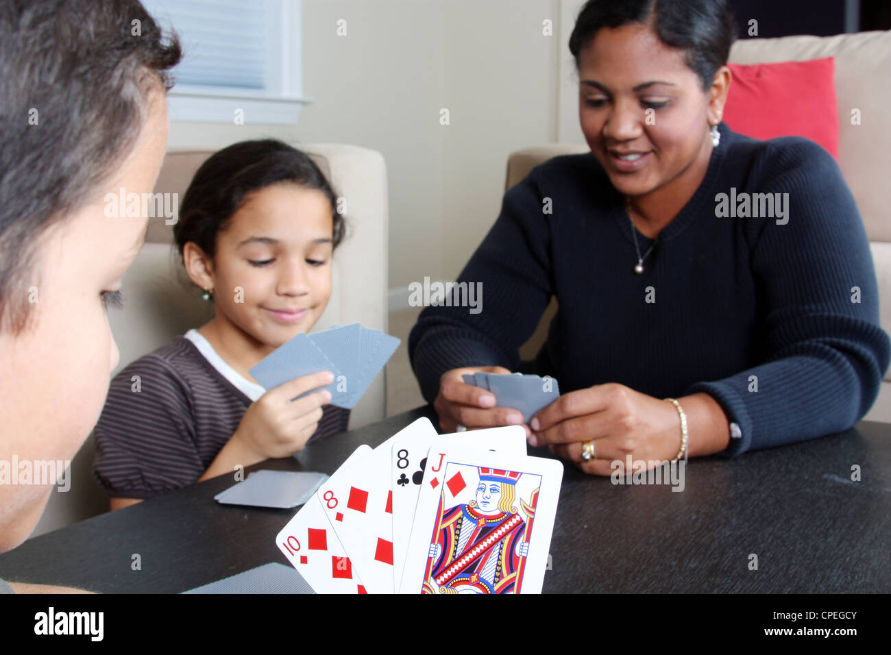 Family playing cards together around the table Stock Photo - Alamy