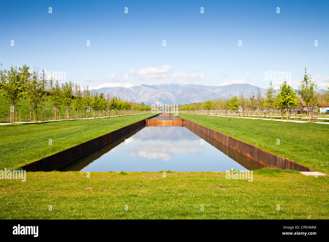 Italy - Water pool in green field with Alps mountains on background ...