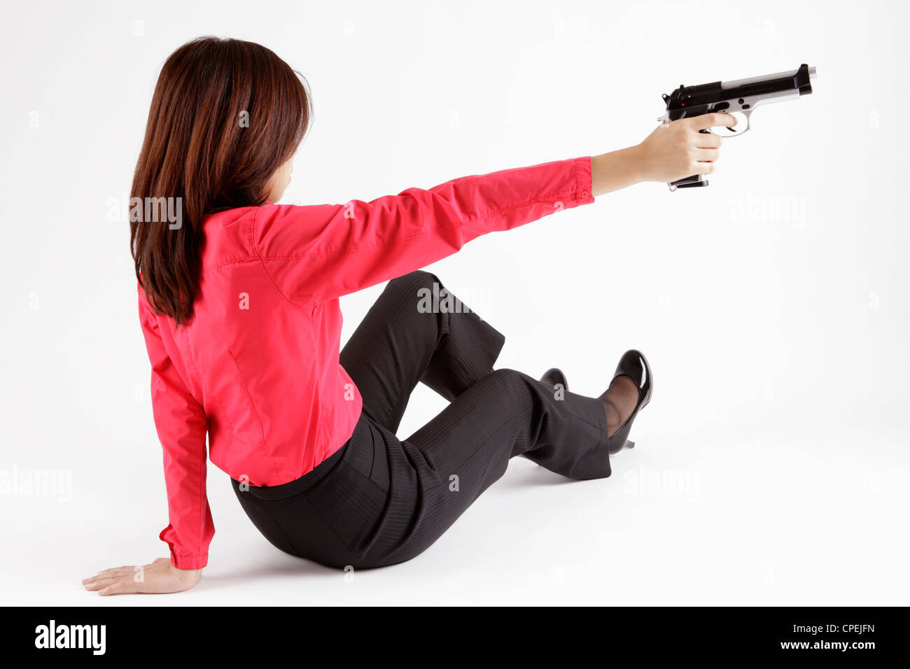 Office lady shoots gun by sitting on ground Stock Photo - Alamy