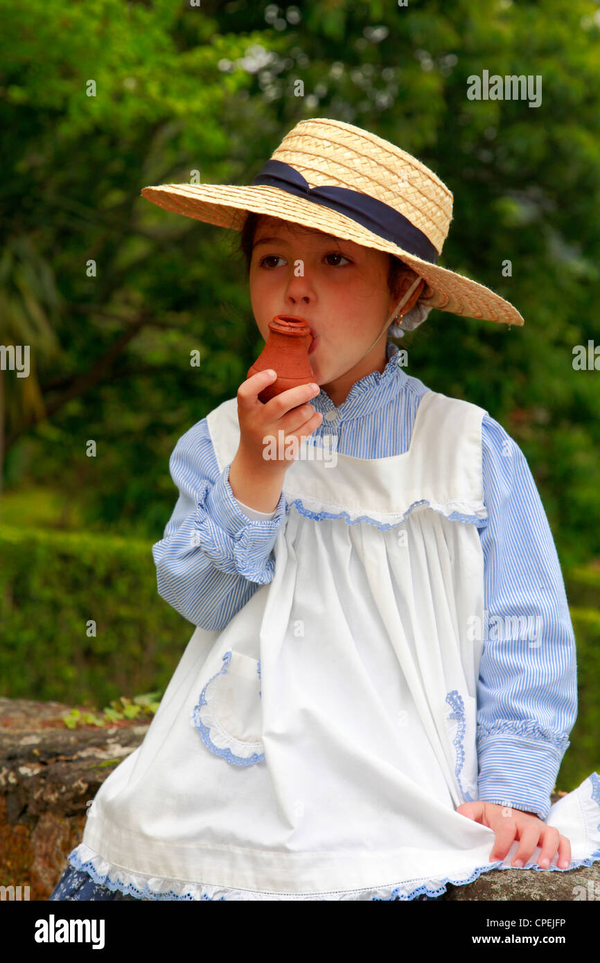 Young girl wearing traditional garments plays with a clay whistle. Sao ...