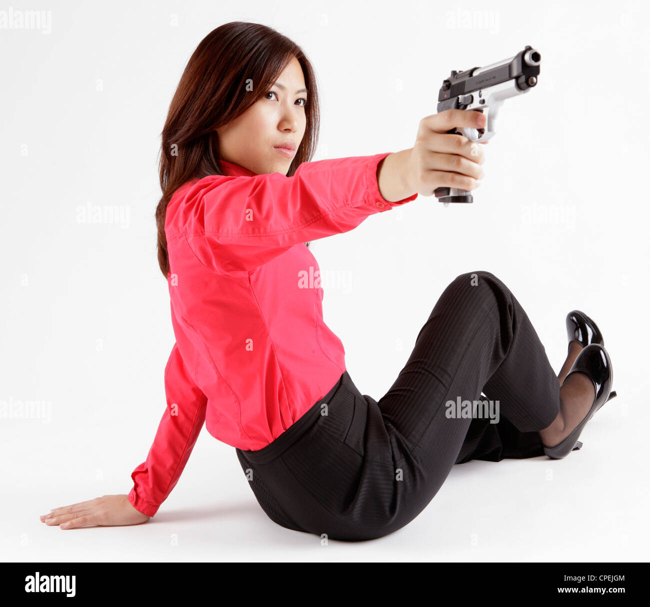 Office lady shoots gun by sitting on ground Stock Photo - Alamy