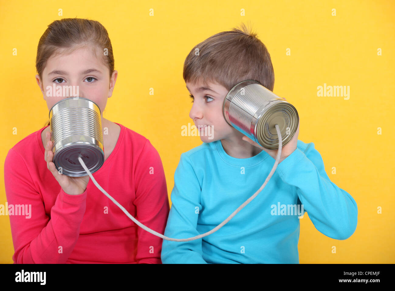 Brother and sister speaking through tin can and string Stock Photo - Alamy