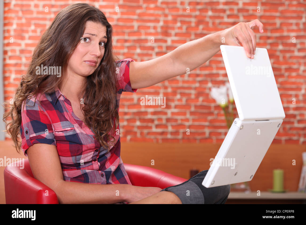 Woman holding her laptop disdainfully Stock Photo - Alamy