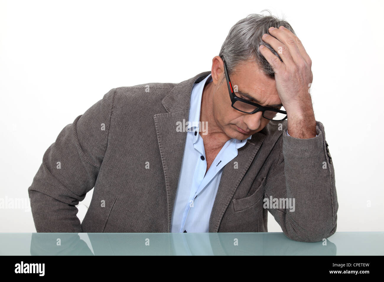 Desperate man sitting at a desk Stock Photo - Alamy