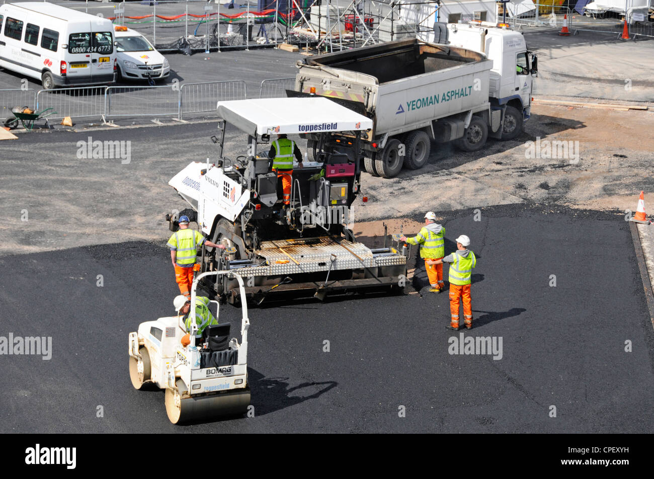 Tipper lorry and Tarmac laying machine with road roller and workmen ...
