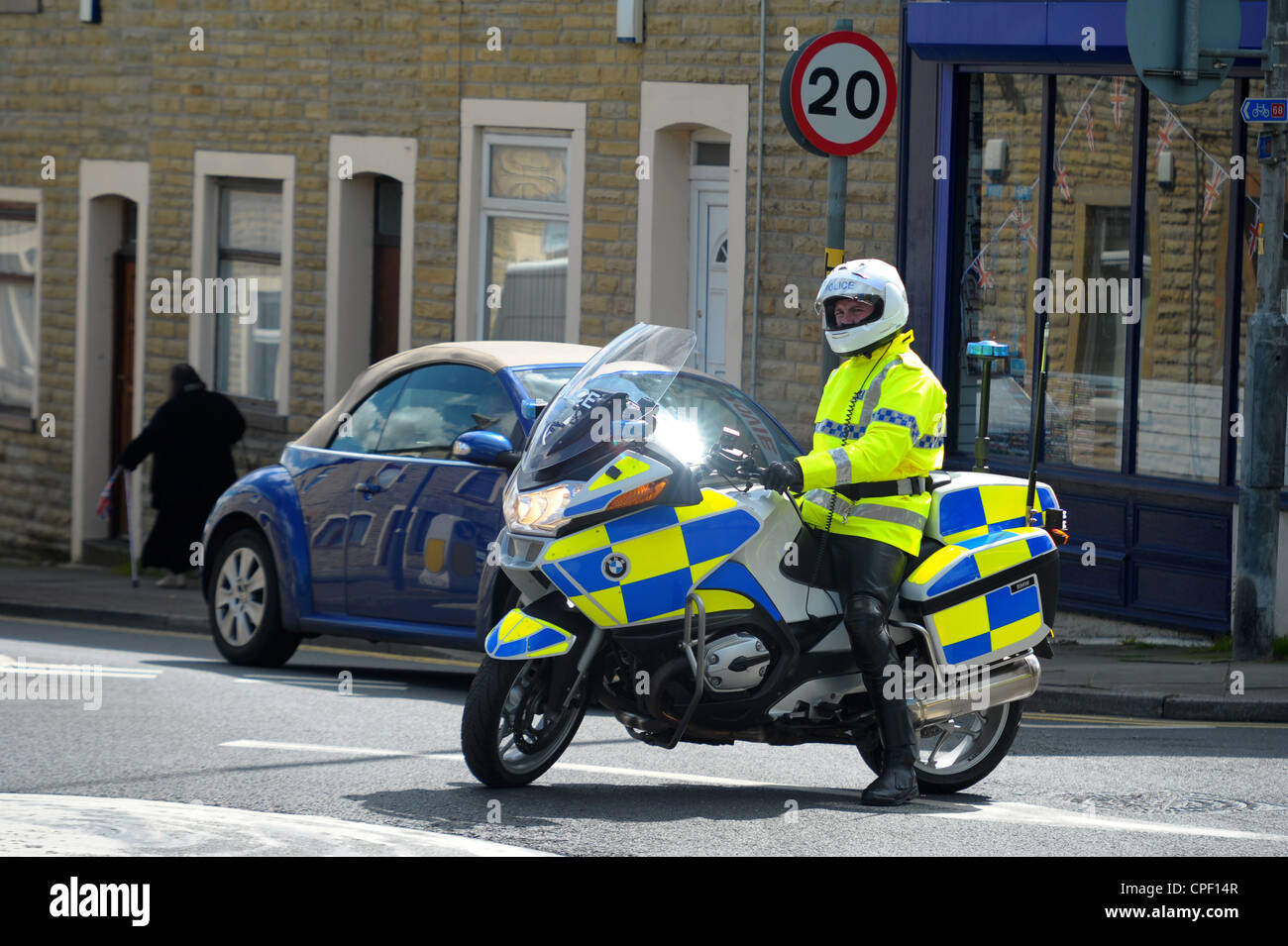 Police motorcyclist stops traffic on a mini roundabout waiting for The ...