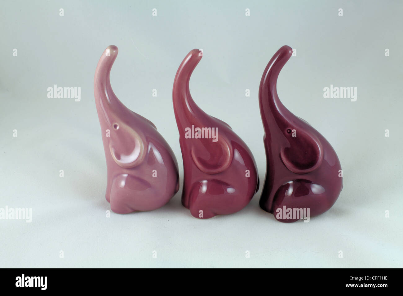 Three pink and purple ceramic elephants in a light tent with white ...