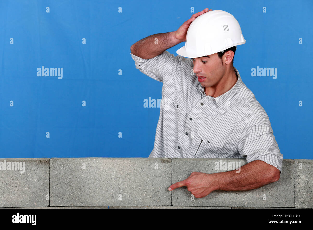 Builder pointing at a block wall Stock Photo - Alamy