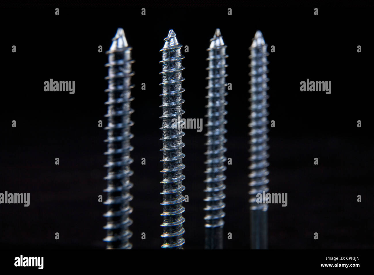 A pattern of four shiny screws set on a black background Stock Photo ...