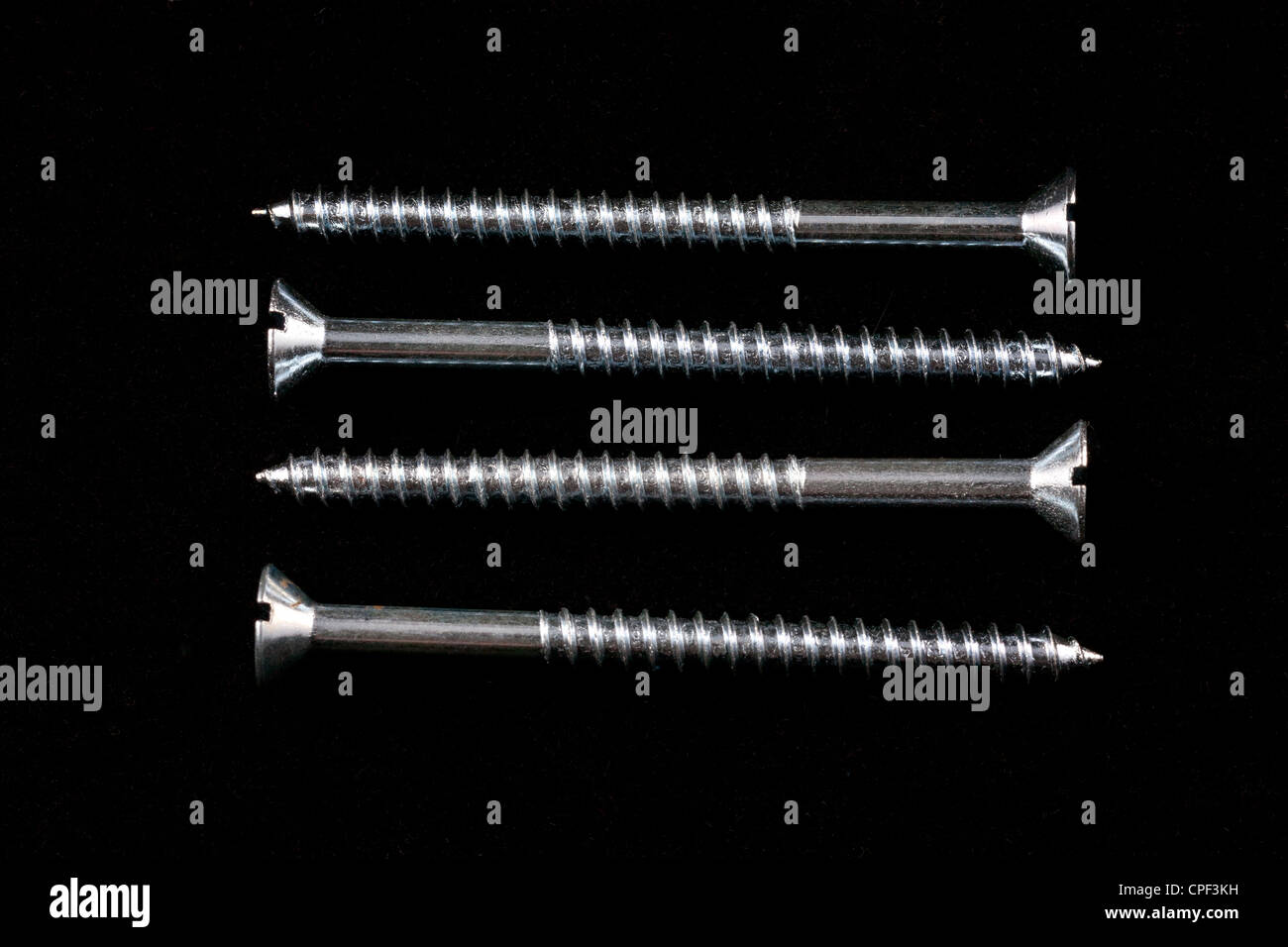 A pattern of four shiny screws set on a black background Stock Photo ...