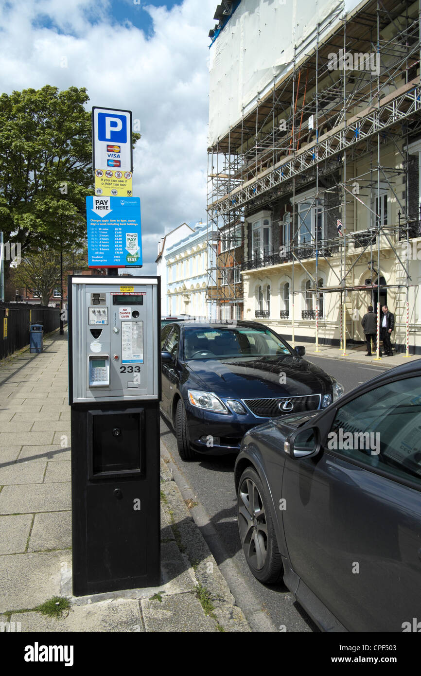 Parking ticket pay machine next to road with cars parked Stock Photo ...
