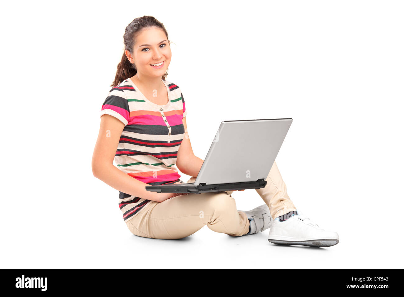 A smiling teenager doing her homework on a laptop isolated on white ...