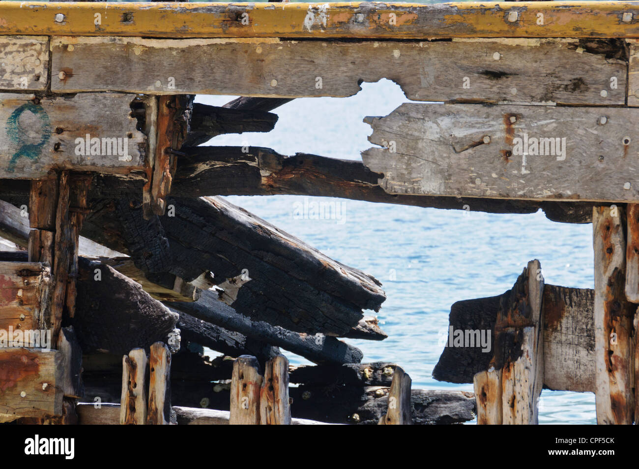 Detail of wooden burnt down shipwreck frames ocean, Muelle Bay Dalaruan ...