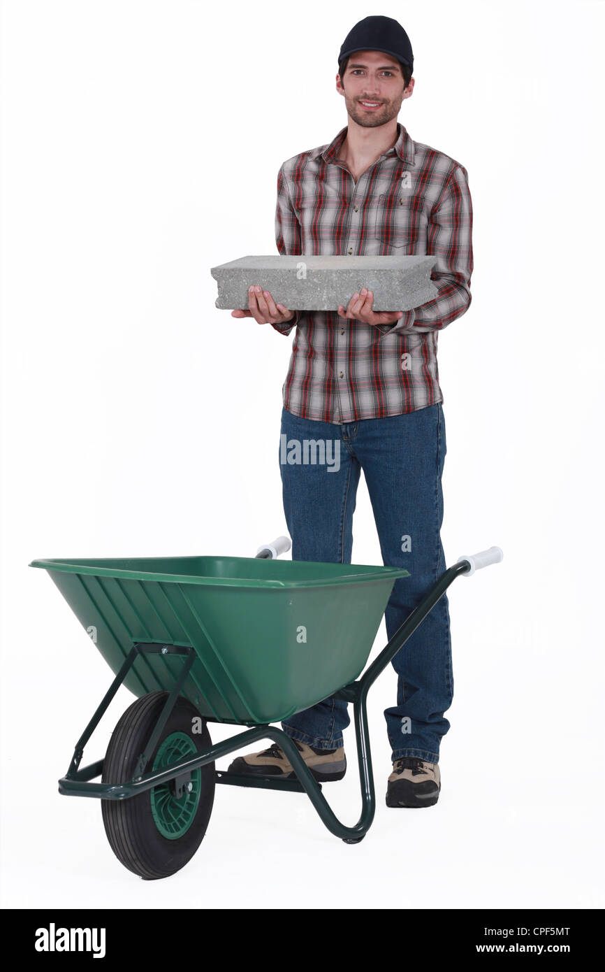Mason placing brick in wheelbarrow Stock Photo - Alamy
