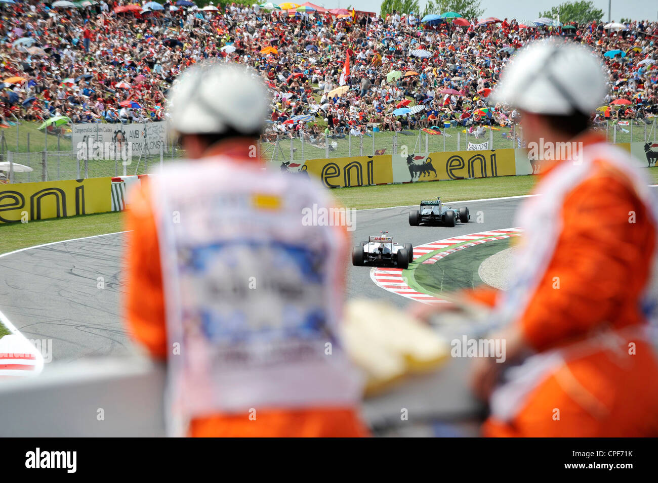 two race cars pass through curve in front of grandstand filled with ...
