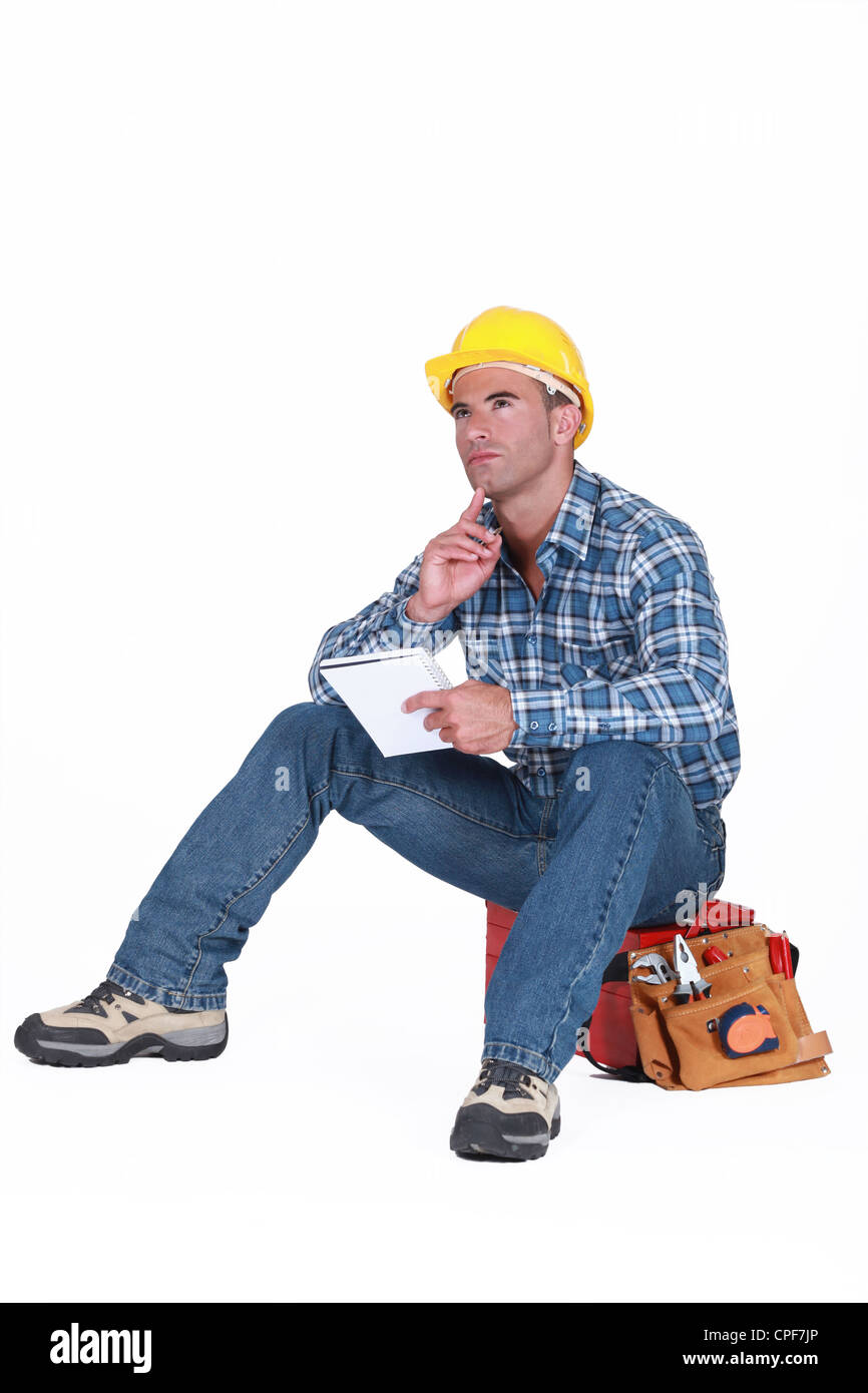Builder sat on tool box thinking Stock Photo - Alamy