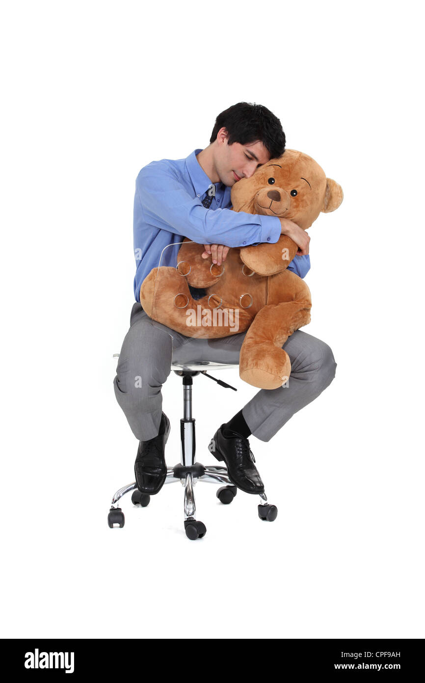 Businessman sat in chair hugging teddy bear Stock Photo - Alamy