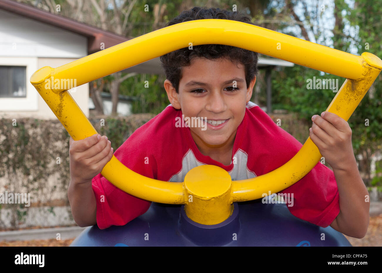 Hispanic boy aged 11 playing in playground on equipment portrait in ...