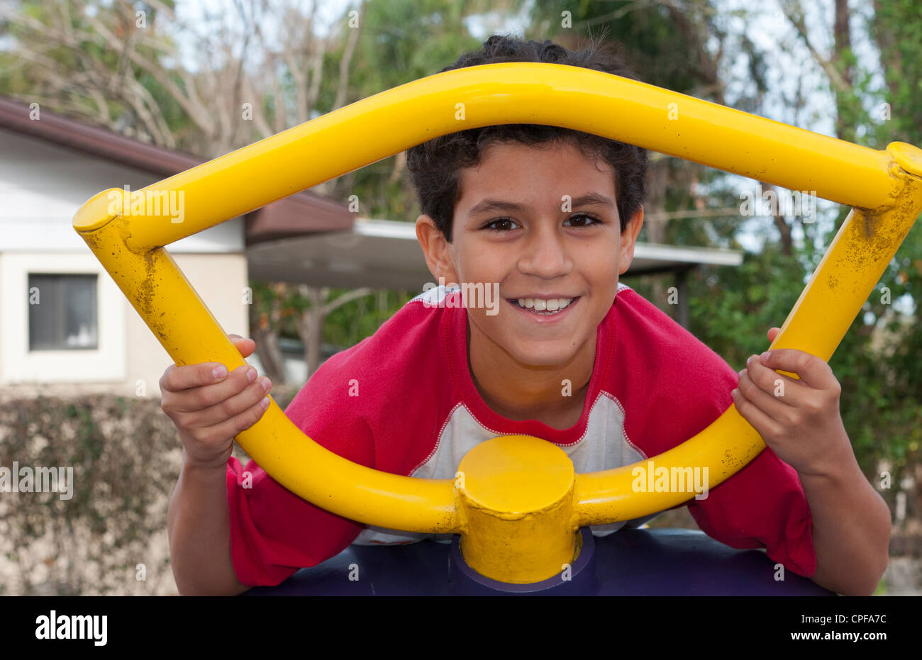Hispanic boy aged 11 playing in playground on equipment portrait in ...