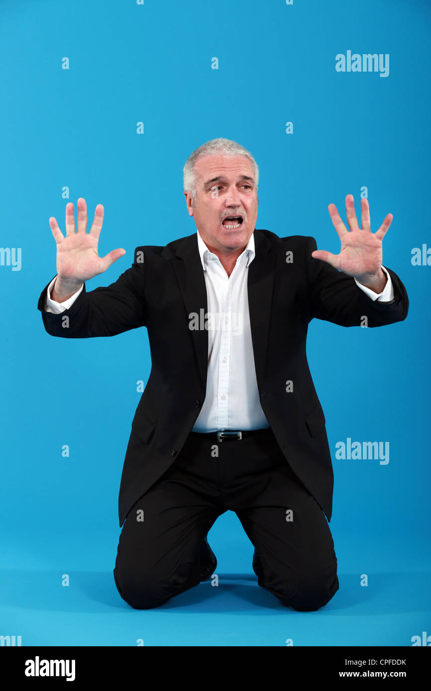 Grey haired businessman begging Stock Photo - Alamy